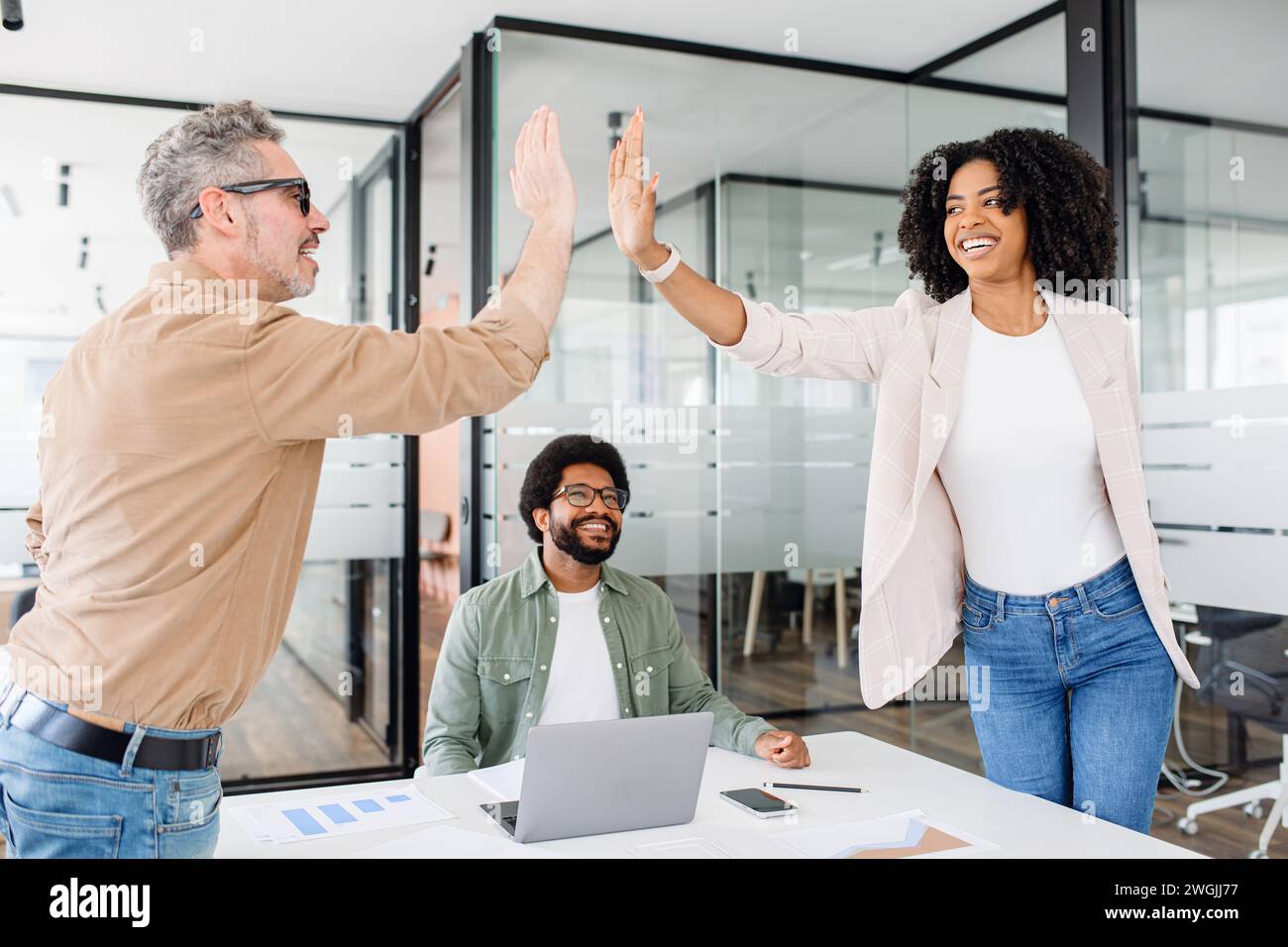 A high-five gesture between colleagues in a modern office space ... A high-five gesture between colleagues in a modern office space ...