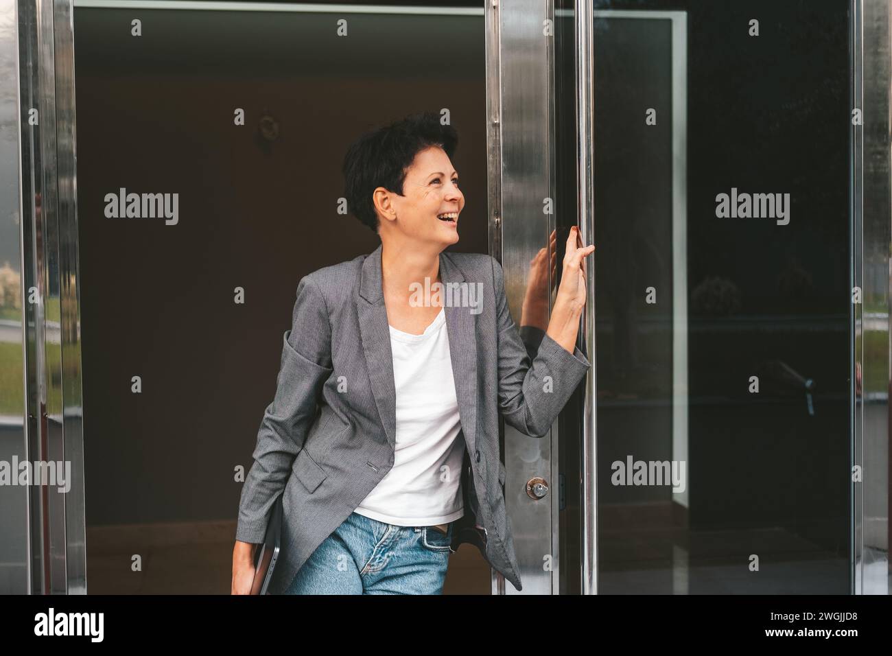 Happy Woman Exiting Building Stock Photo - Alamy
