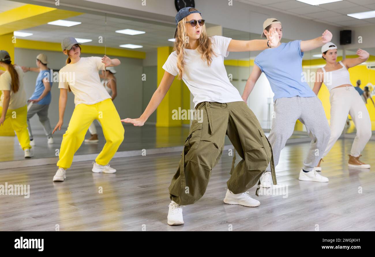 Cool active teenage girls and boy learning dance movements during group ...