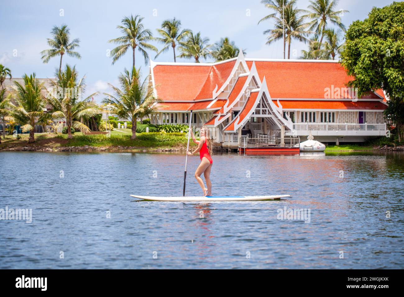Woman paddleboarding on calm lake with tropical scenery. Outdoor ...