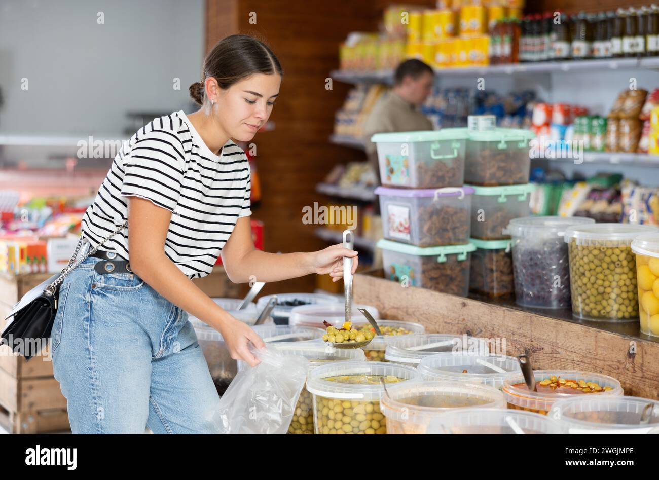 Young girl chooses marinated olives in supermarket, scooping them from ...