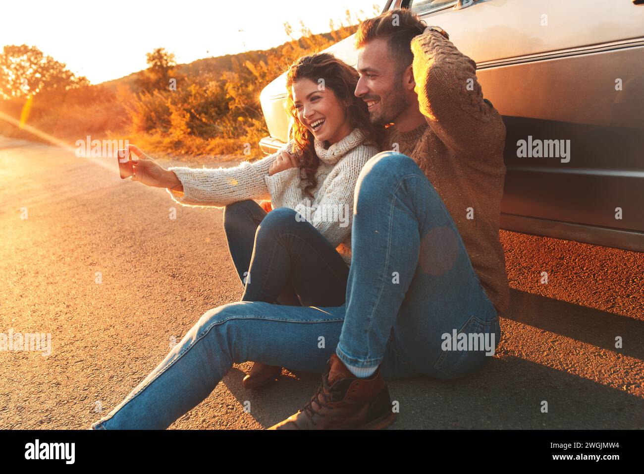 Beautiful couple on road trip, they are taking a break from driving ...
