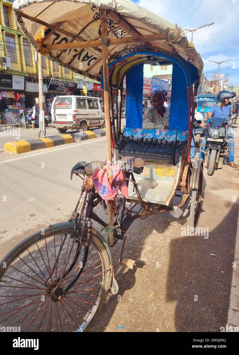 A rickshaw driver is framed in the rear window of the adjoining ...