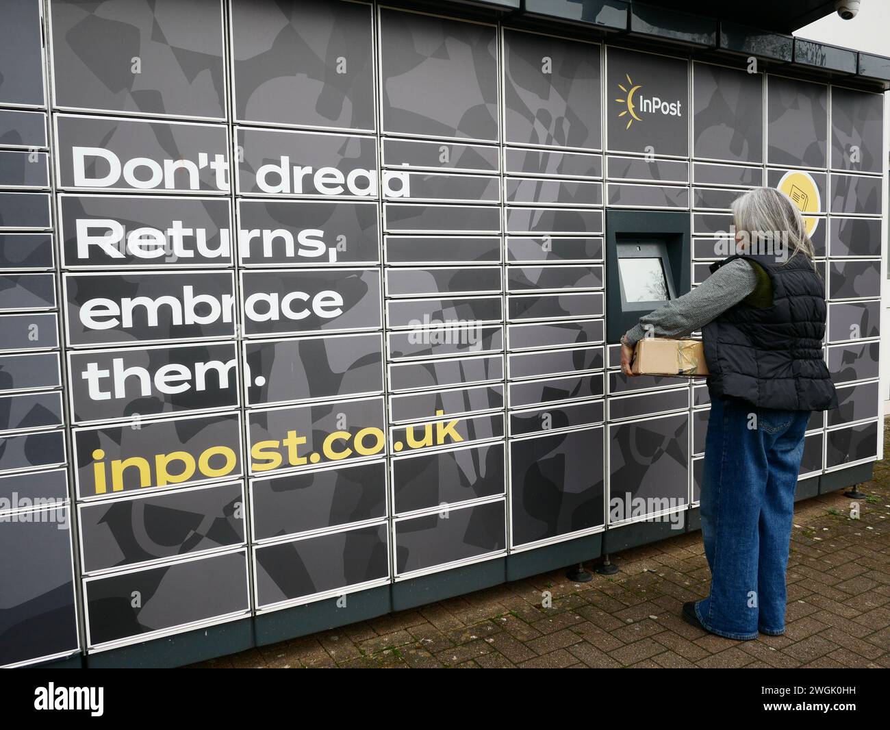 Woman using InPost parcel lockers to send packages and return items ...