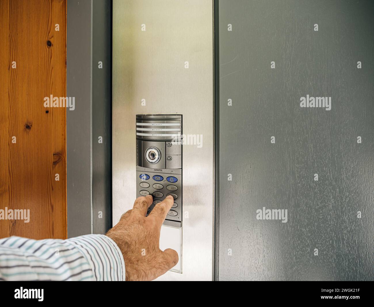 A man presses the access code on the intercom device to enter his house ...