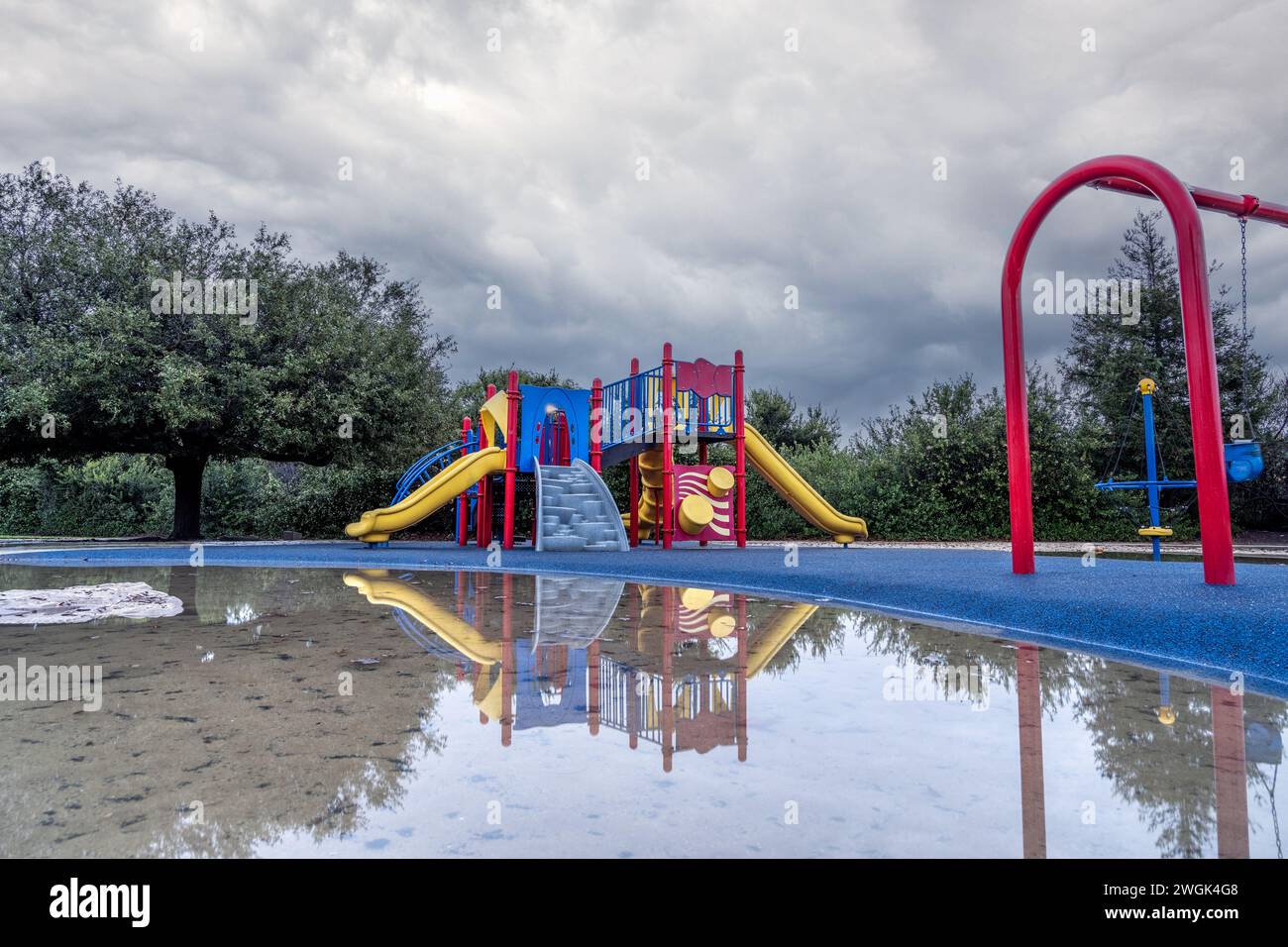 Park playground has a big pond of rain water trapped over the sand and ...
