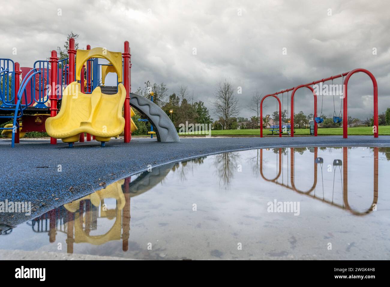 Park playground has a big pond of rain water trapped over the sand as ...