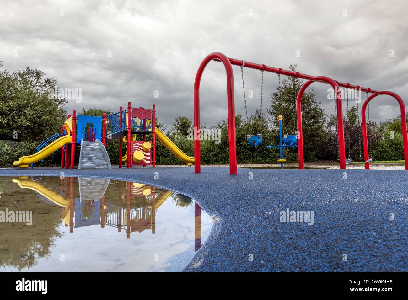 Park playground has a big pond of rain water trapped over the sand ...