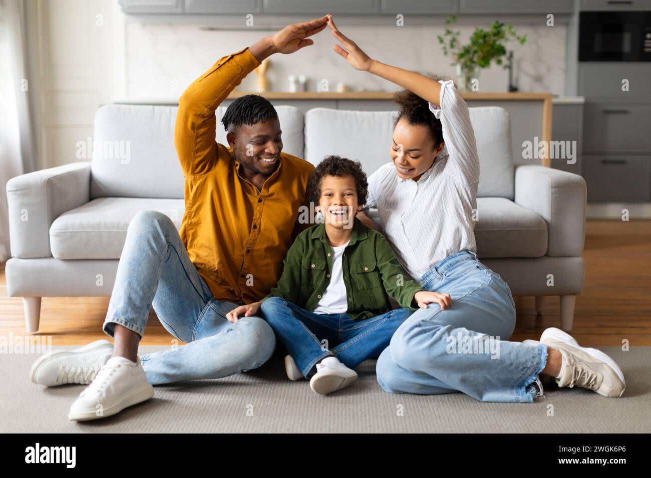 Black family forms house shape with hands, sitting on floor Stock Photo ...