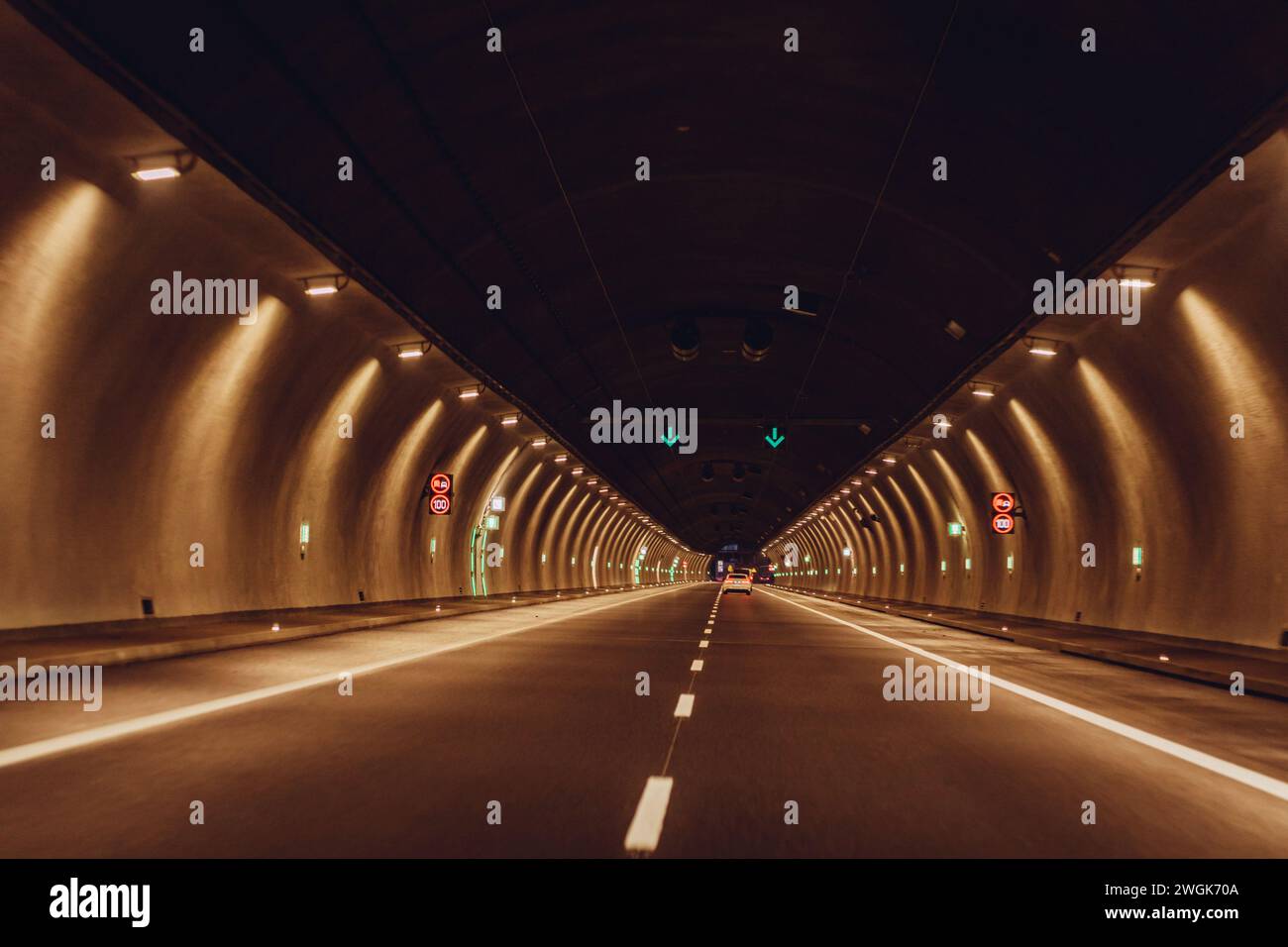 Underground road tunnel, night illuminated concrete long tube with car ...