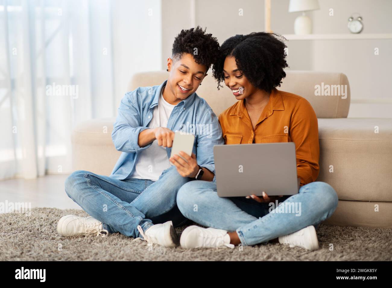 A young couple engages with technology in a bright living space ...