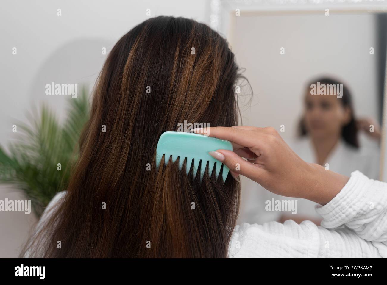 Home Haircare: woman combs her long, healthy hair in front of a mirror ...