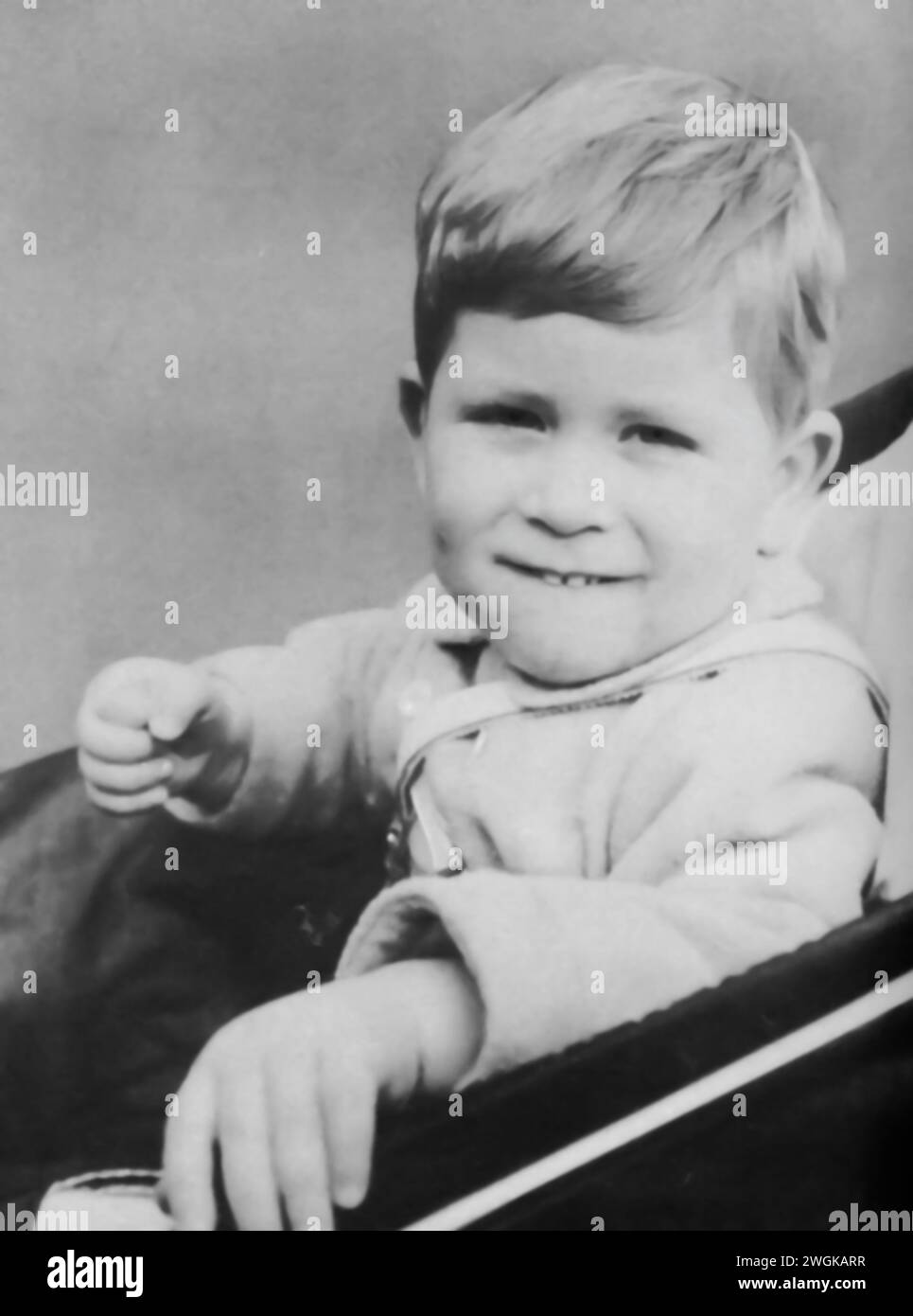 A young Charles III, posing for the camera while seated in his baby ...