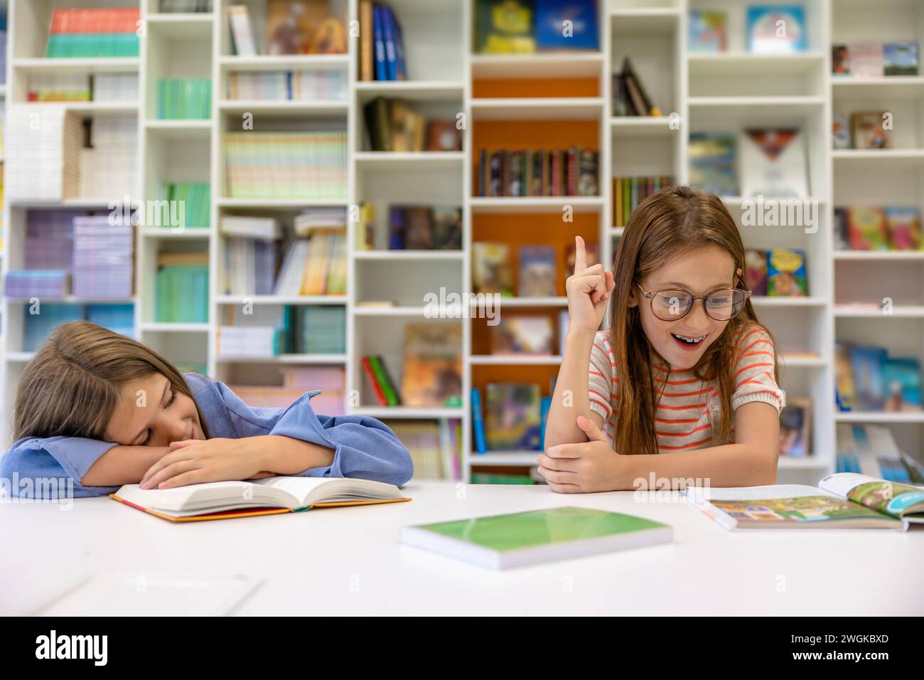 Girls reading in school library, little pupil feeling tired and falling ...