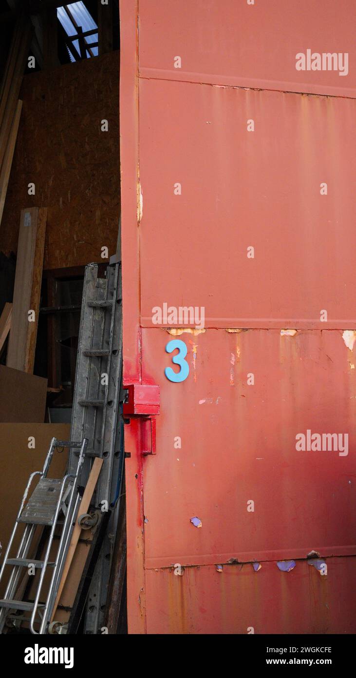 Orange red door with large blue number 3 on an industrial unit Stock ...