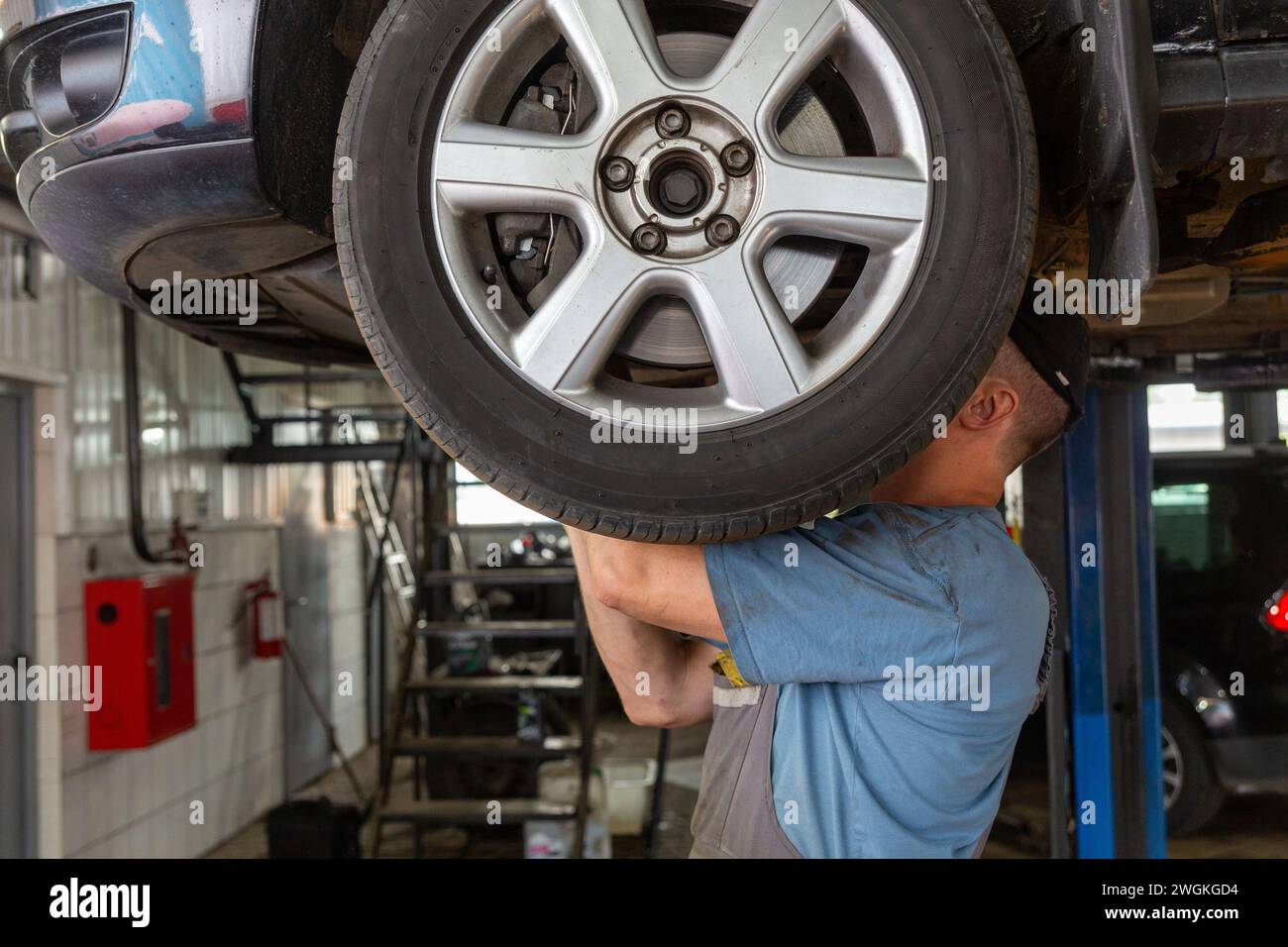 Car mechanic working in auto repair shop. Man in uniform working with ...