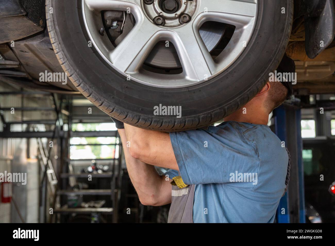 Car mechanic working in auto repair shop. Man in uniform working with ...