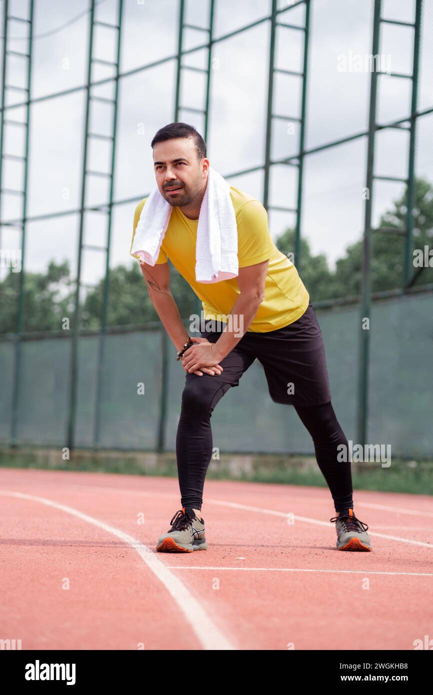 Sportive man with towel on neck doing forward lunge exercising on ...