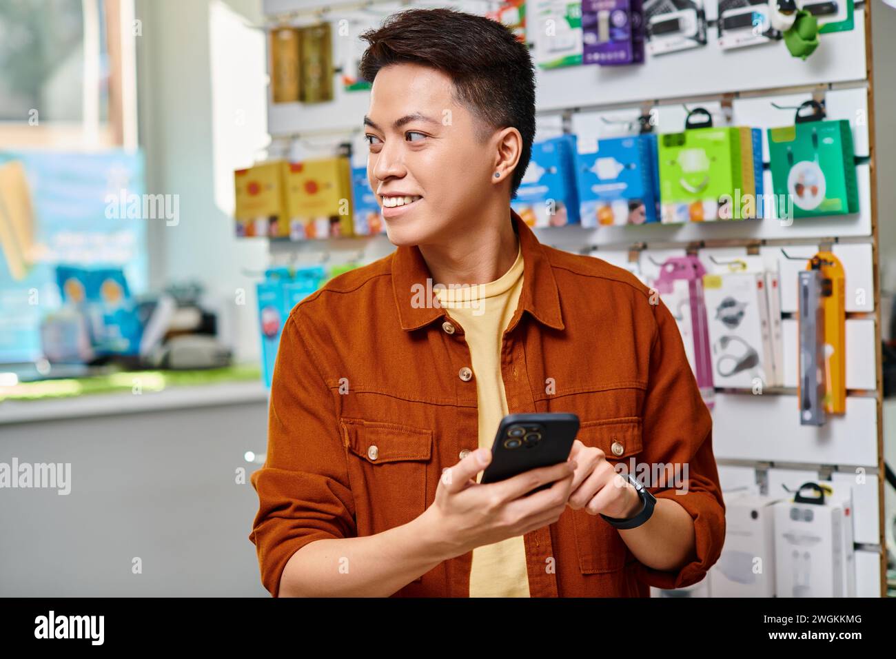 pleased asian entrepreneur holding mobile phone and looking away in ...