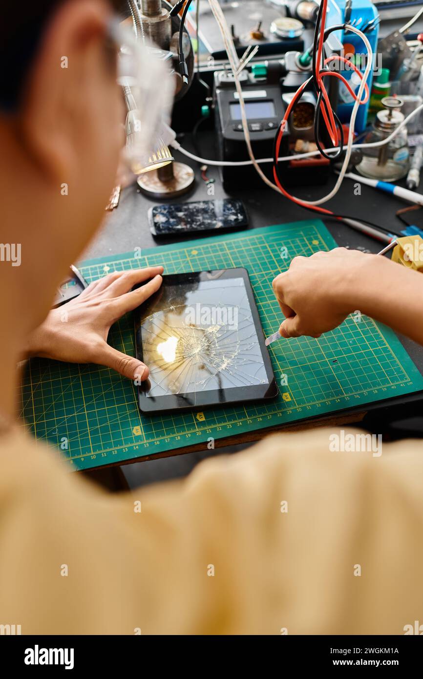 back view of skilled repairman removing broken screen of digital tablet ...