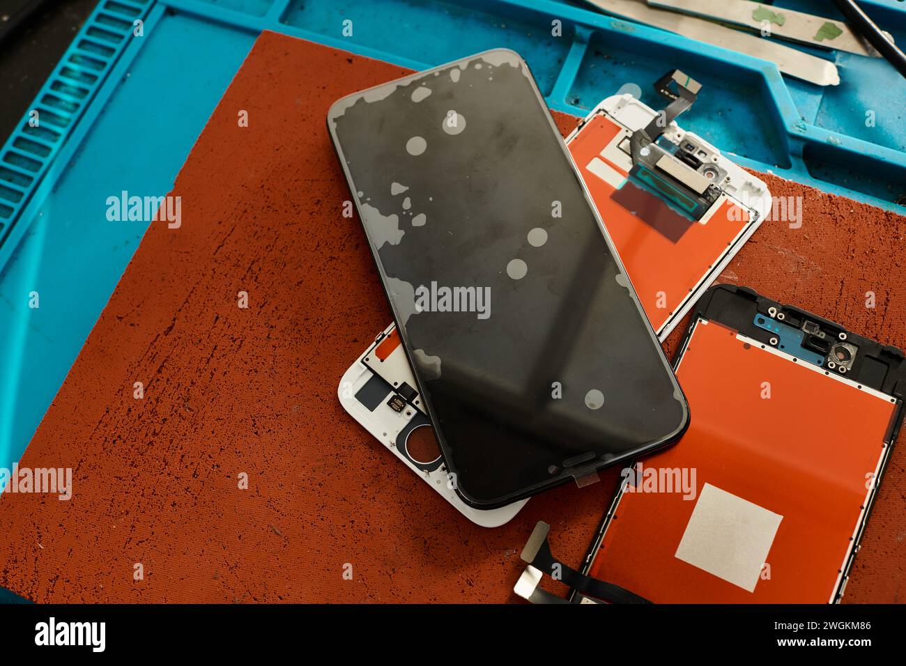 top view of smartphone and spare touchscreens on work desk in repair ...