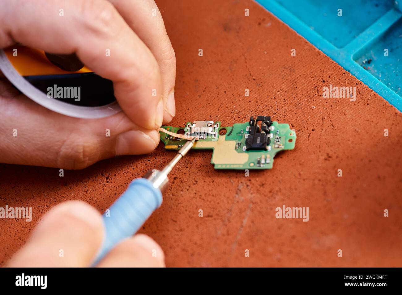 partial view of technician soldering electronic microscheme in repair ...