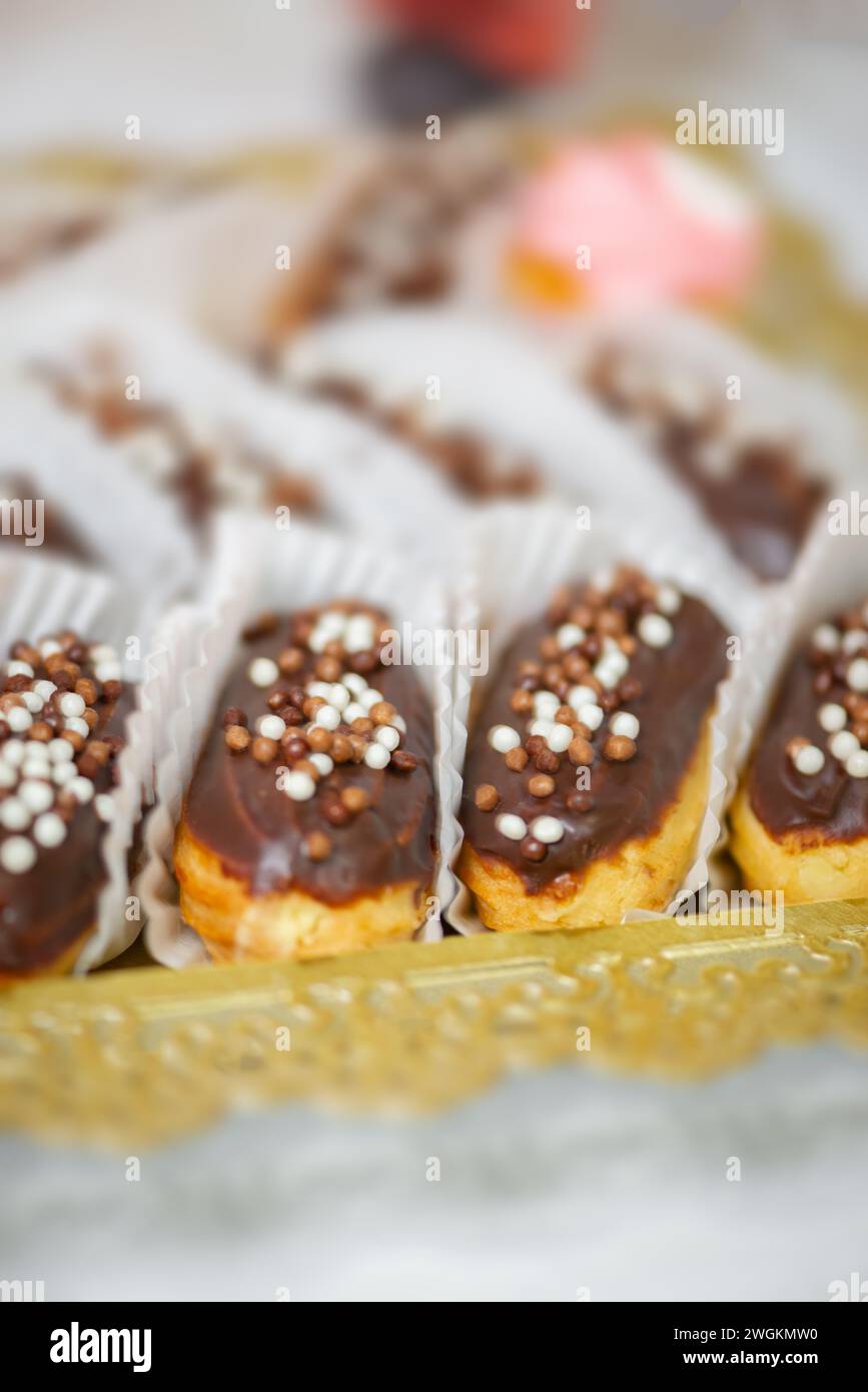 Small eclairs sweets backed pastry with colorful sprinkles close up ...