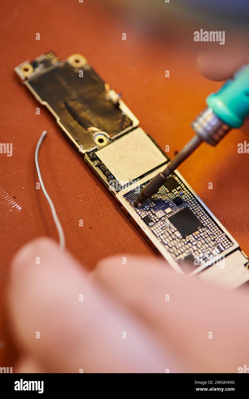 cropped view of technician soldering chipset of modern electronic ...