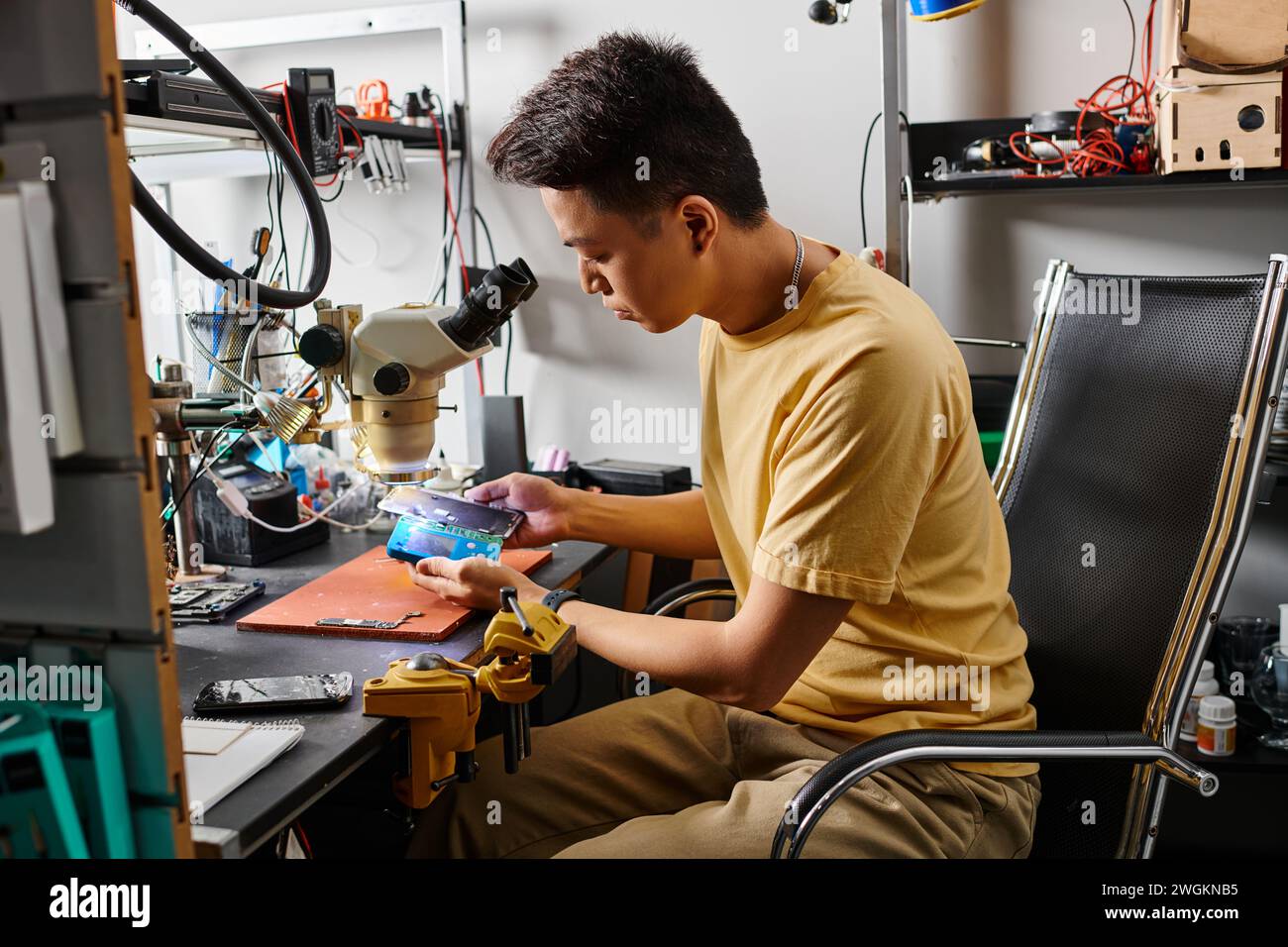 asian technical specialist making diagnostics of broken phone with ...