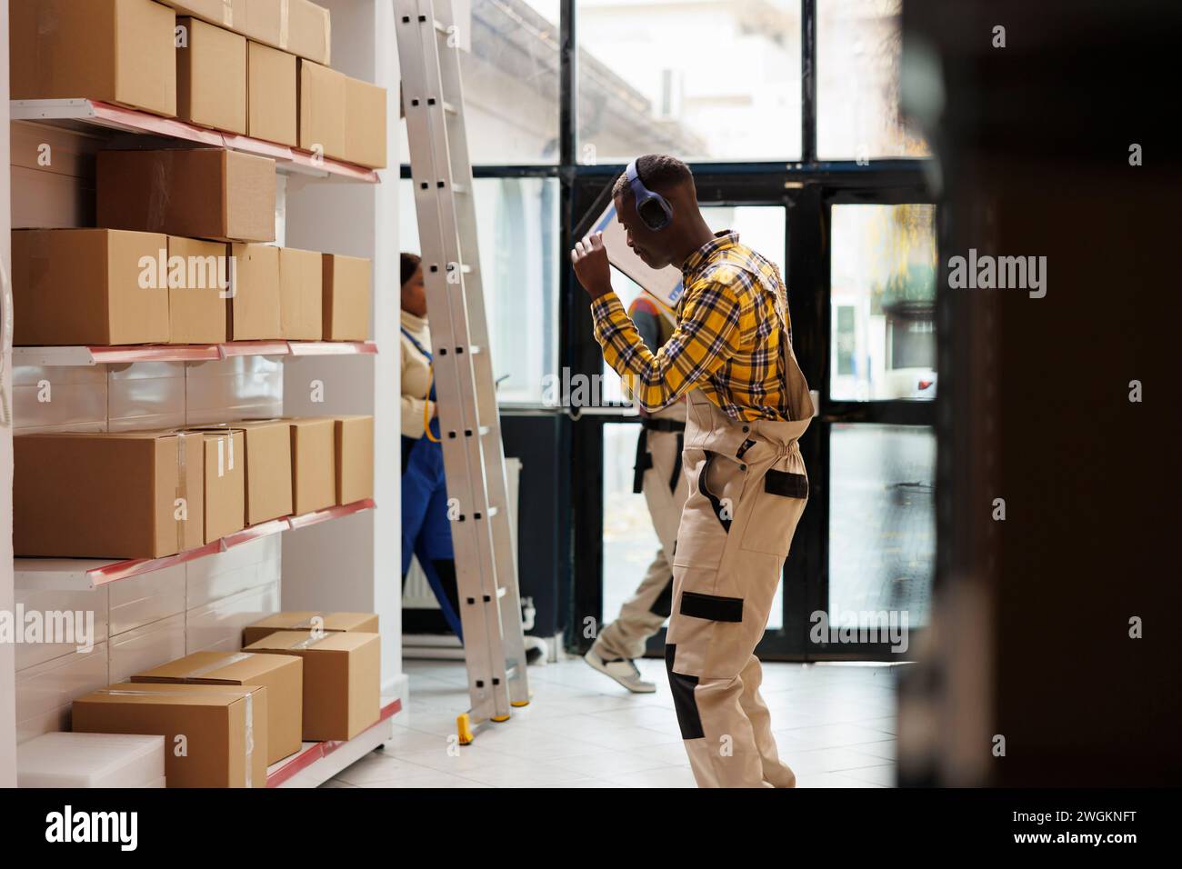 Delivery manager wearing overall dancing in warehouse aisle and ...