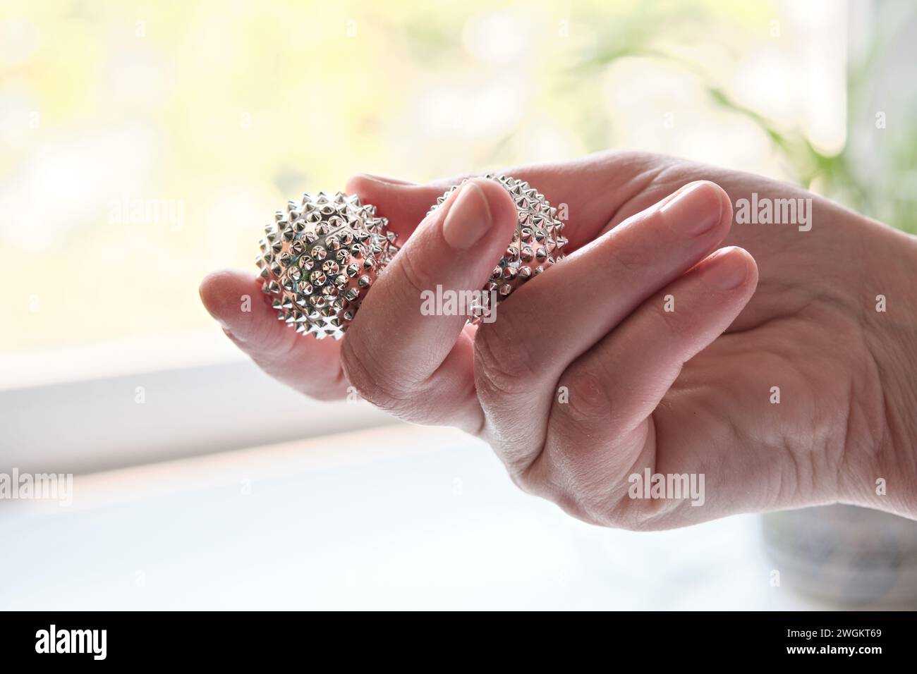 Silver metal magnetic balls in female hand. Spiky tool for hand massage ...
