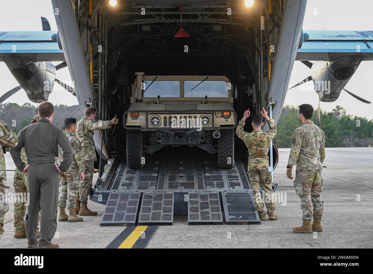 Airmen assigned the 19th Airlift Wing guide a Humvee onto a C-130J ...