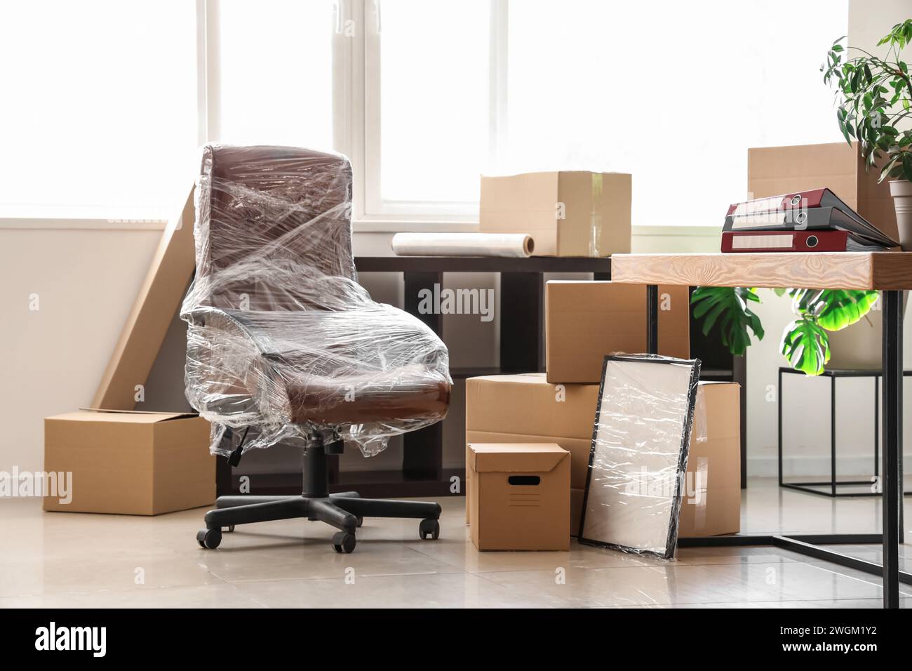 Interior of light office with chair wrapped in stretch film and ...
