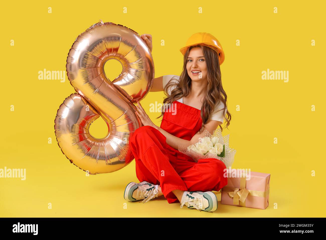 Female mechanic with bouquet of white tulips, gift box and balloon in ...