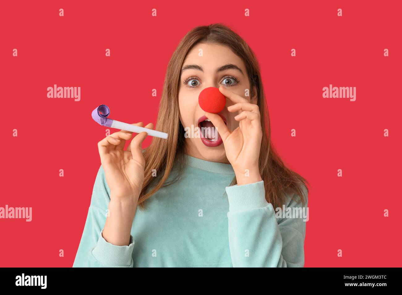 Beautiful young shocked woman with funny clown nose and party whistle ...