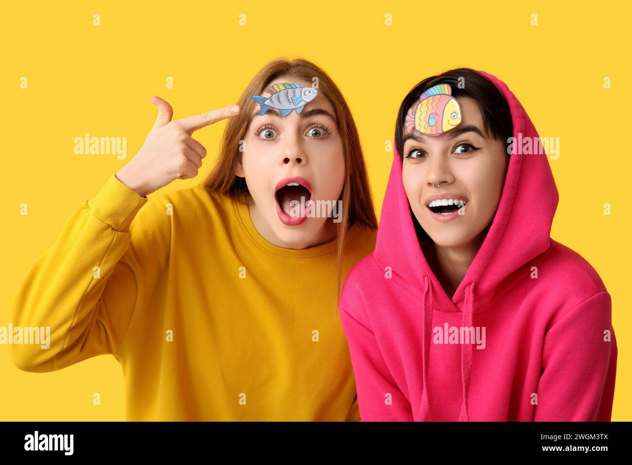 Beautiful young shocked women with paper fishes attached to their ...