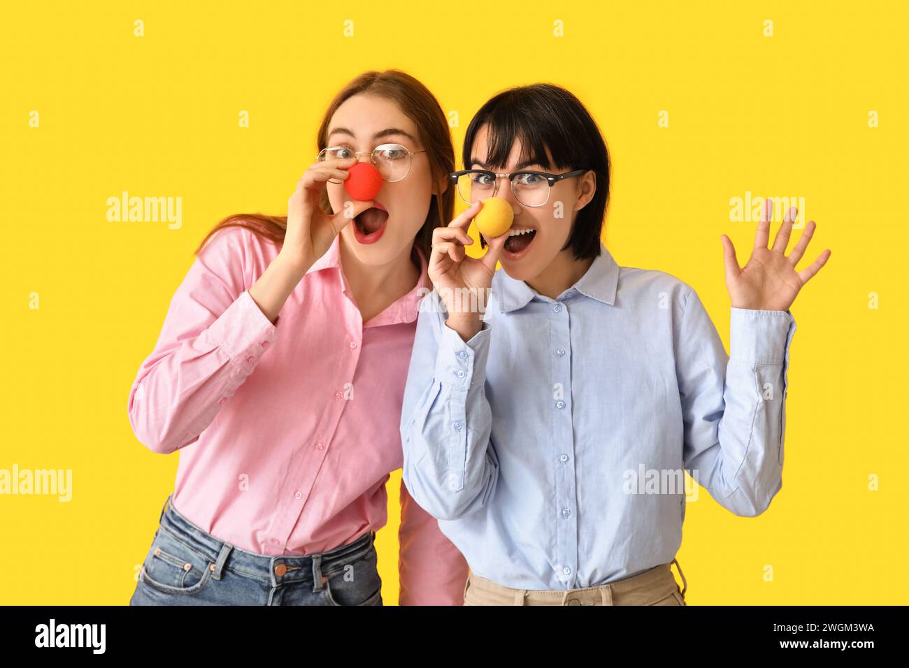 Beautiful young shocked women with funny clown noses on yellow ...