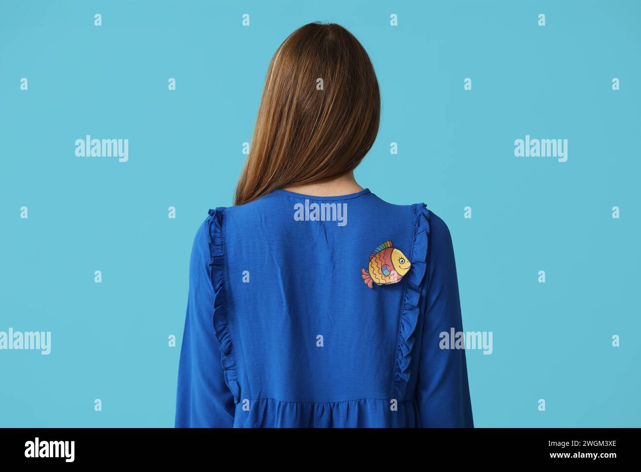 Beautiful young woman with paper fish attached to her back on blue ...