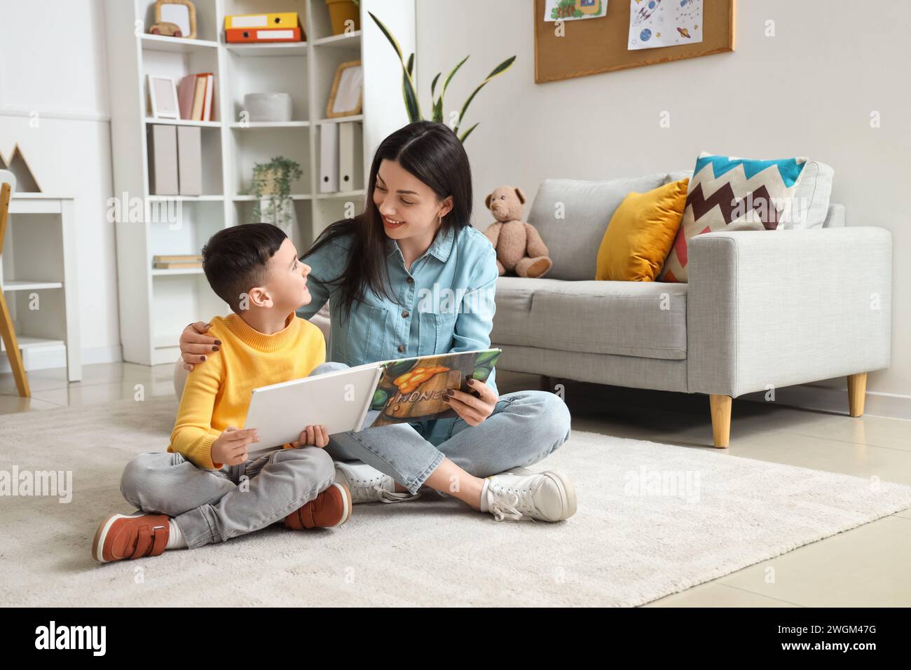 Female psychologist with little boy reading book in office Stock Photo ...