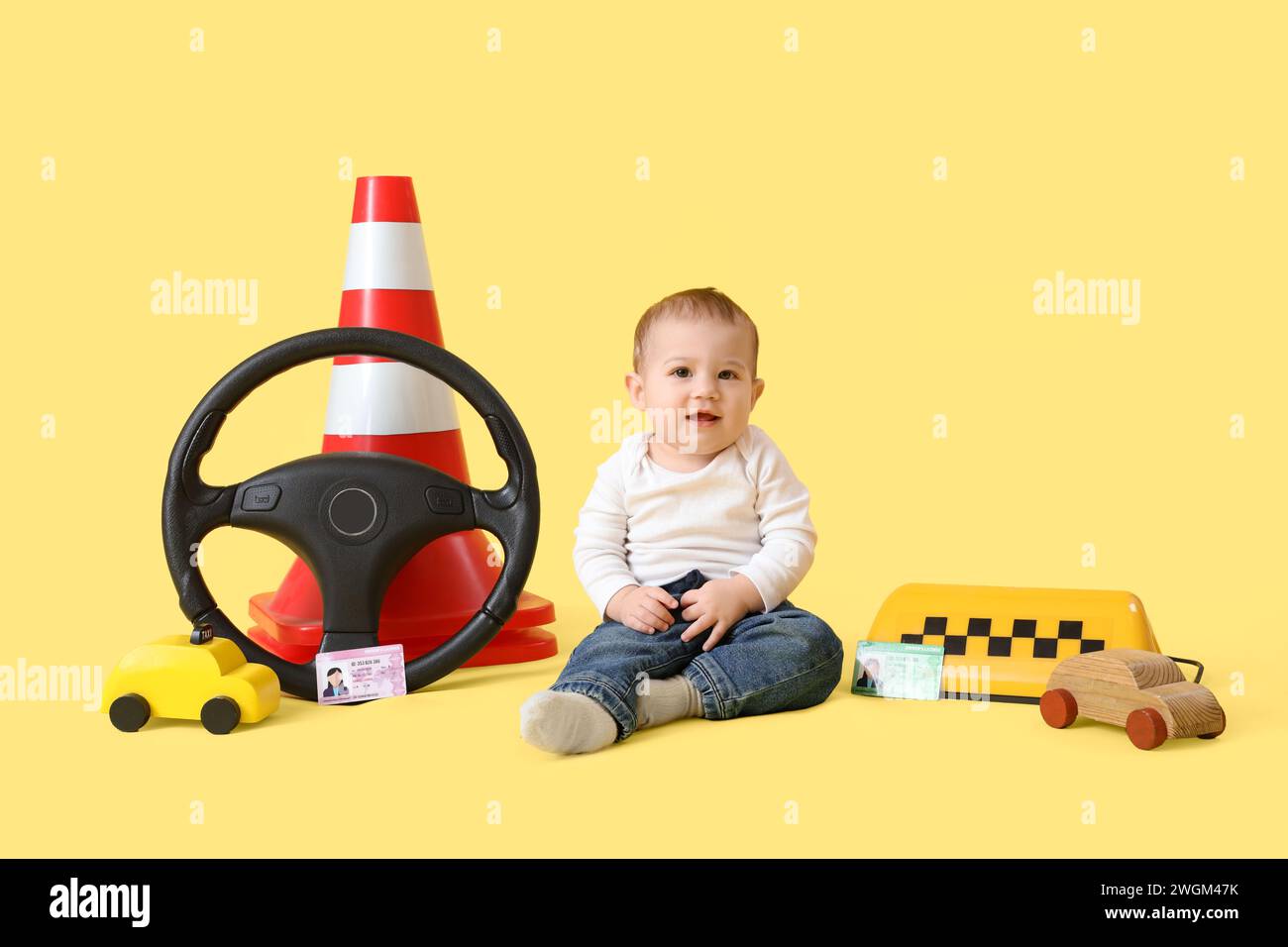 Cute baby taxi driver with accessories on yellow background Stock Photo ...
