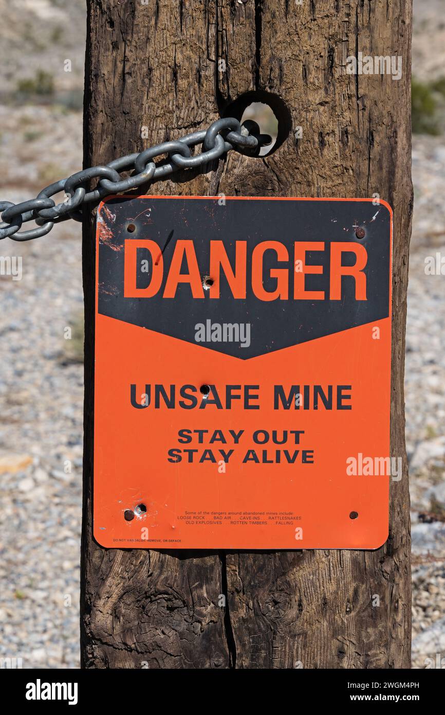 orange and black danger unsafe mine sign on a wood post with a few ...
