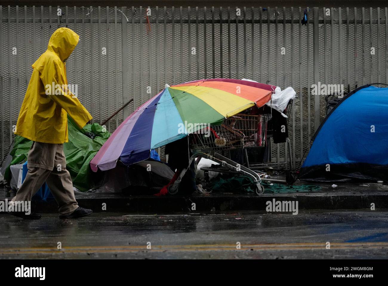 A man walks under heavy rain past temporary tents in Skid Row, one of ...