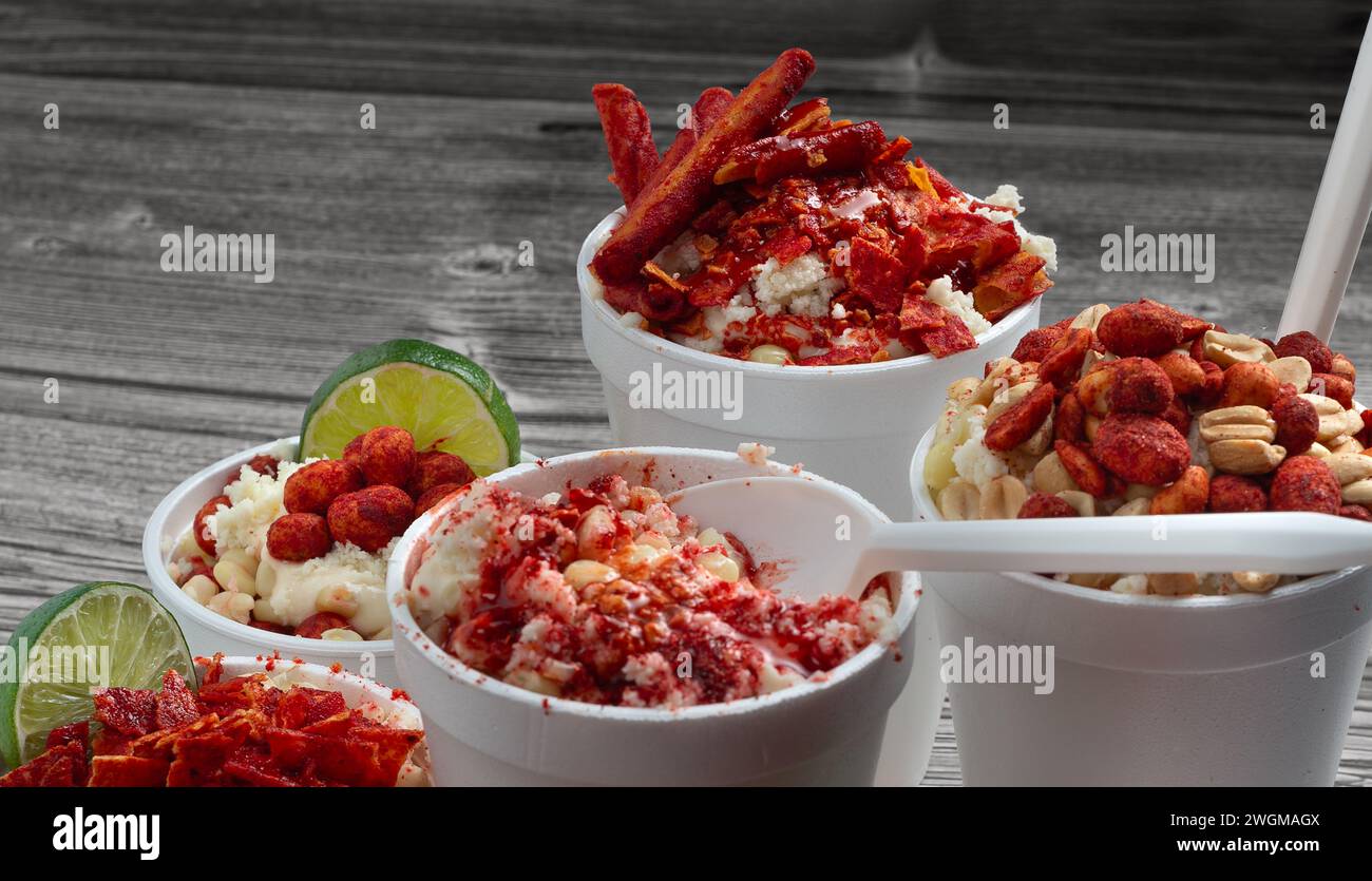 group of Mexican snacks, several corns in cups, prepared with chili ...