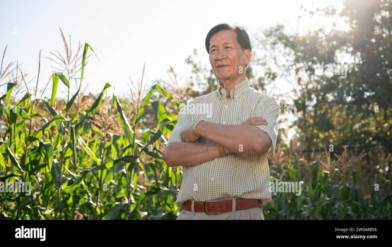 Senior successful and experienced Asian farmer or farm owner stands ...
