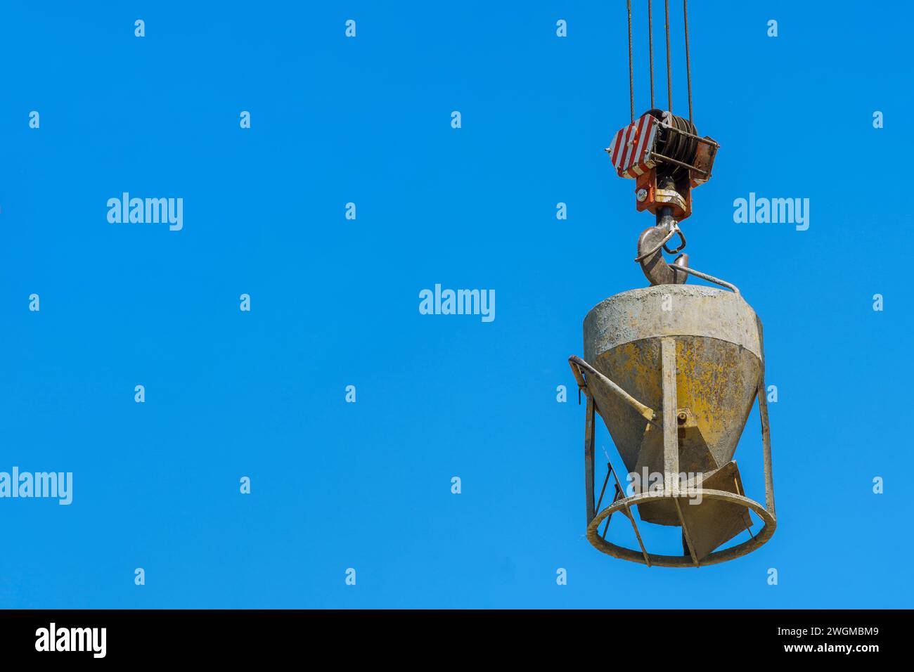 Tower crane lifting a concrete bucket for pour of concrete cement mix ...