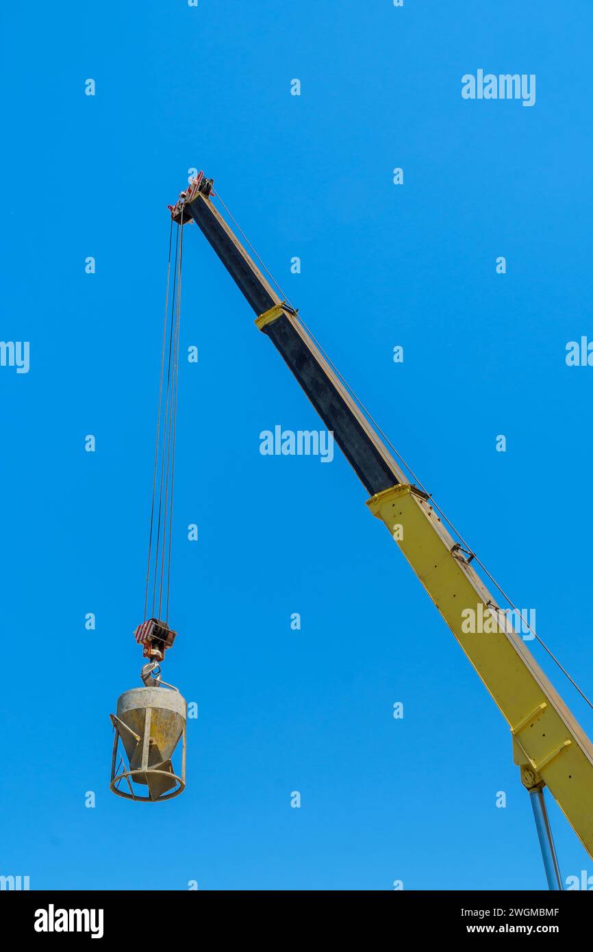 At construction site, tower crane is lifting concrete bucket to pour ...