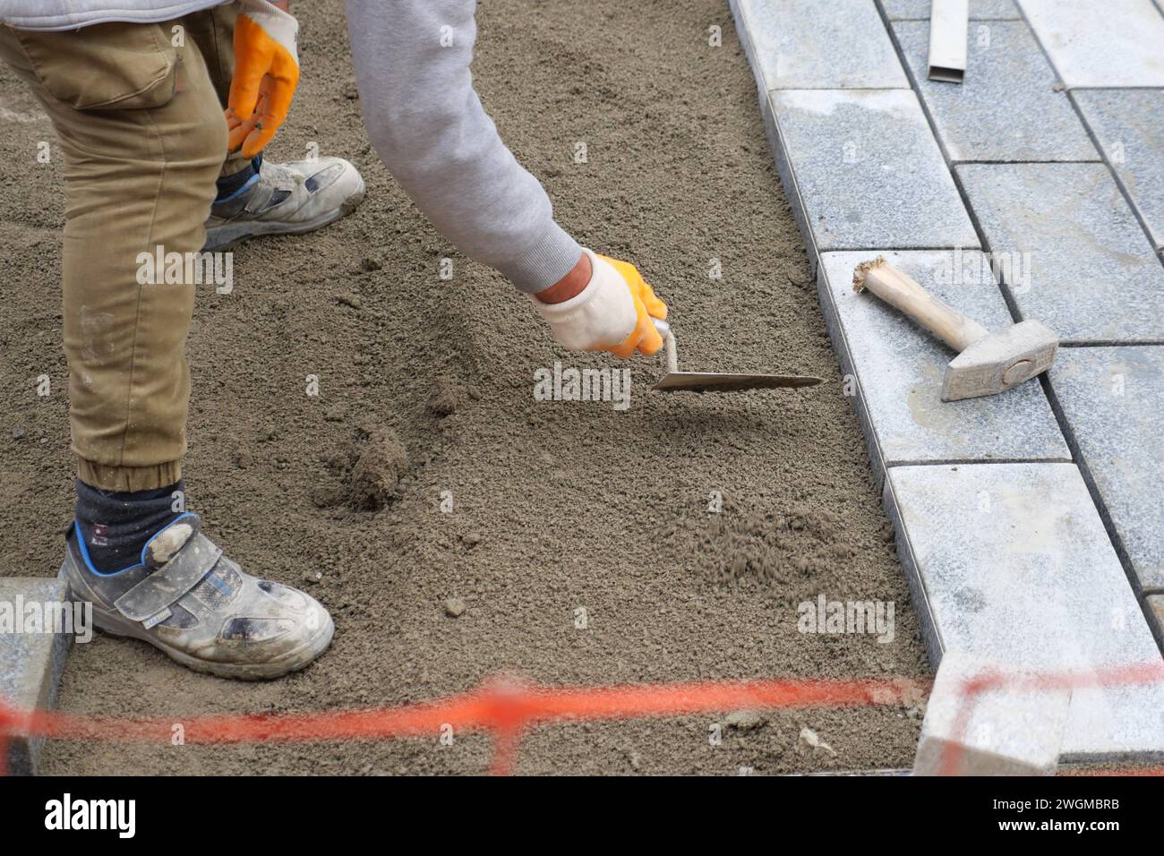 laying concrete bricks on each other for building a new sidewalk in ...