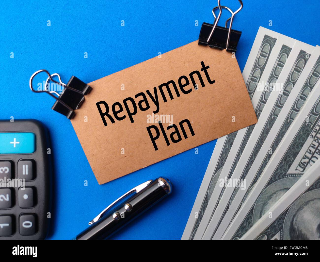 Top view calculator,pen,banknotes and brown card with text Repayment ...