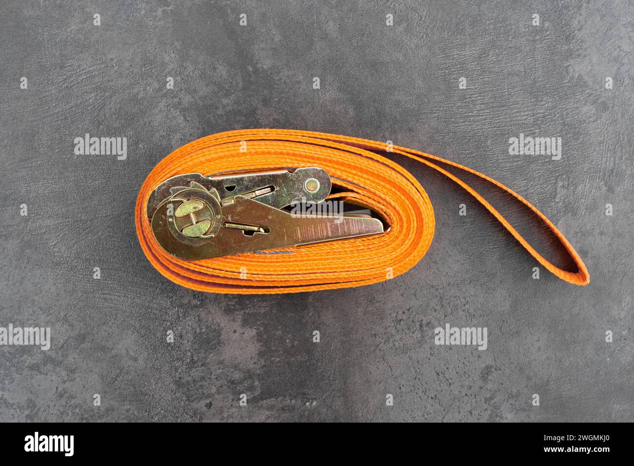 An orange tie-down strap for securing a load, rolled into a roll on a ...