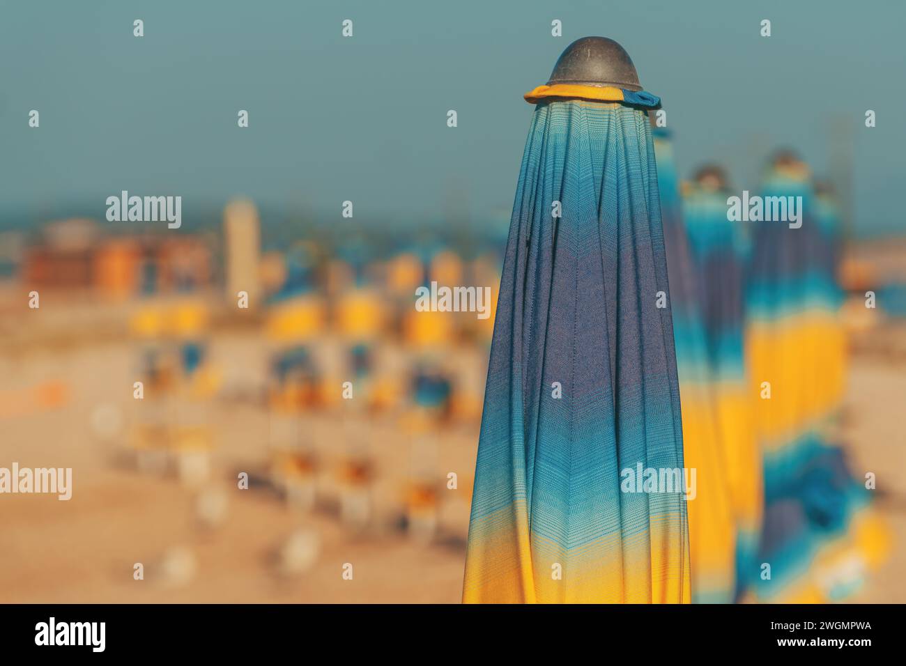 Folded colorful beach umbrella parasols on Adriatic sea coast in sunny ...